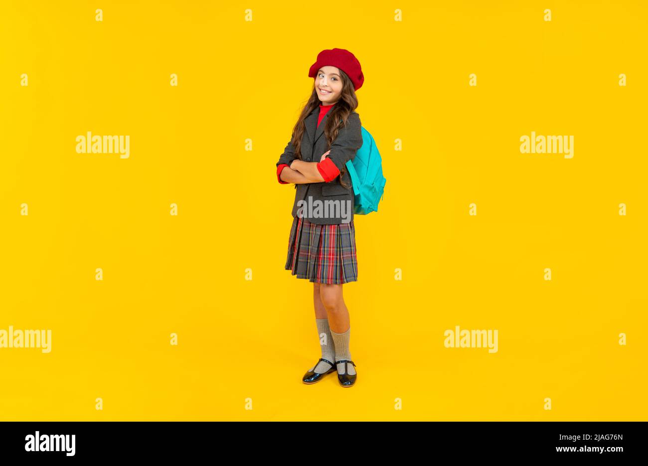 happy kid in school uniform with beret and backpack on yellow ...