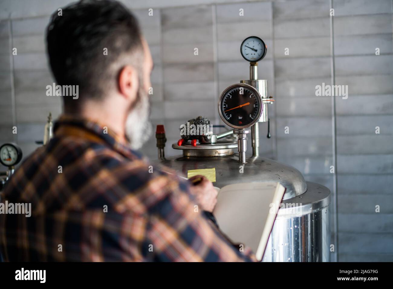 Man is working at craft beer factory. He is operating machinery in ...