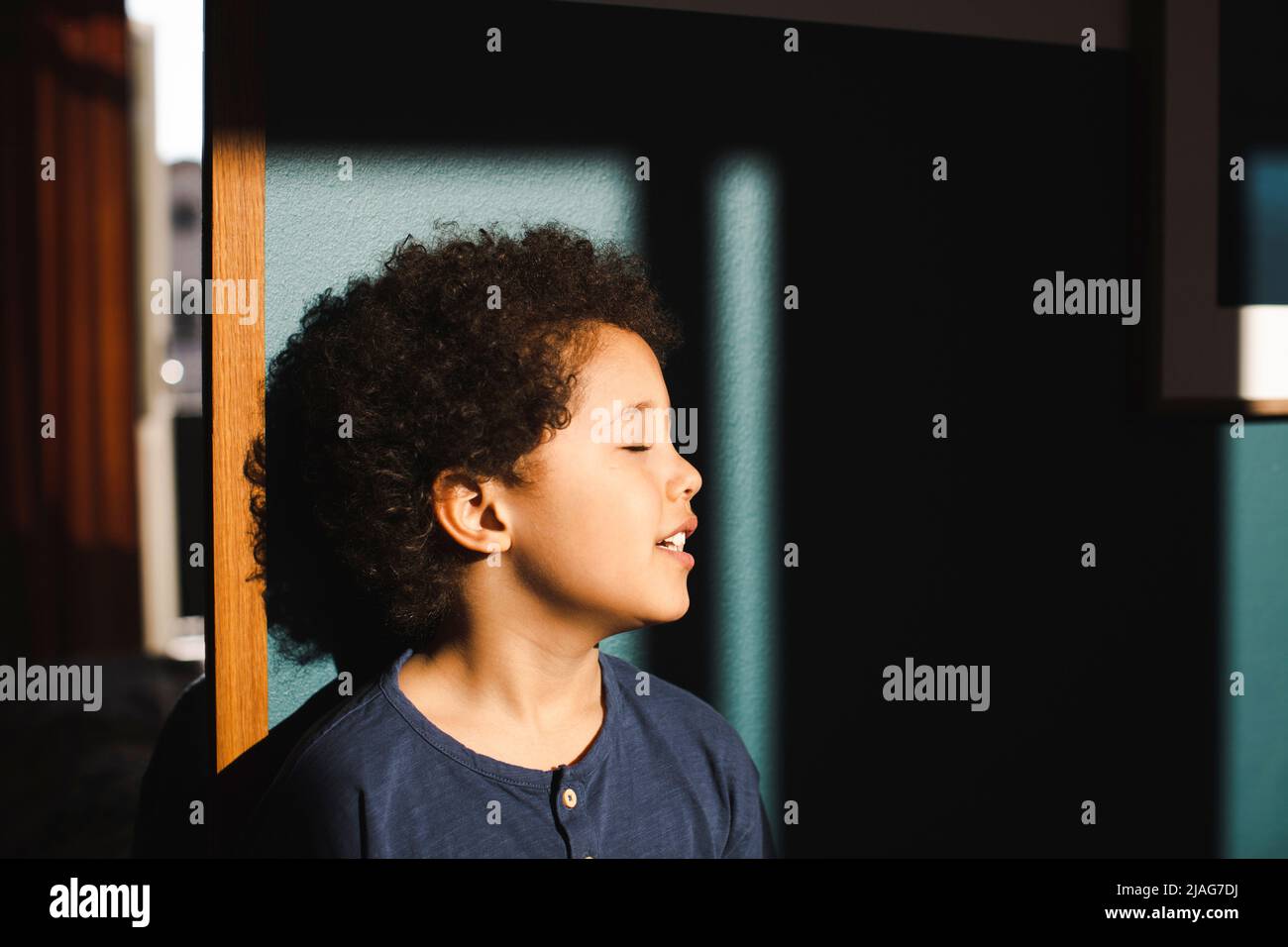 Boy with eyes closed in front of wall at home Stock Photo - Alamy
