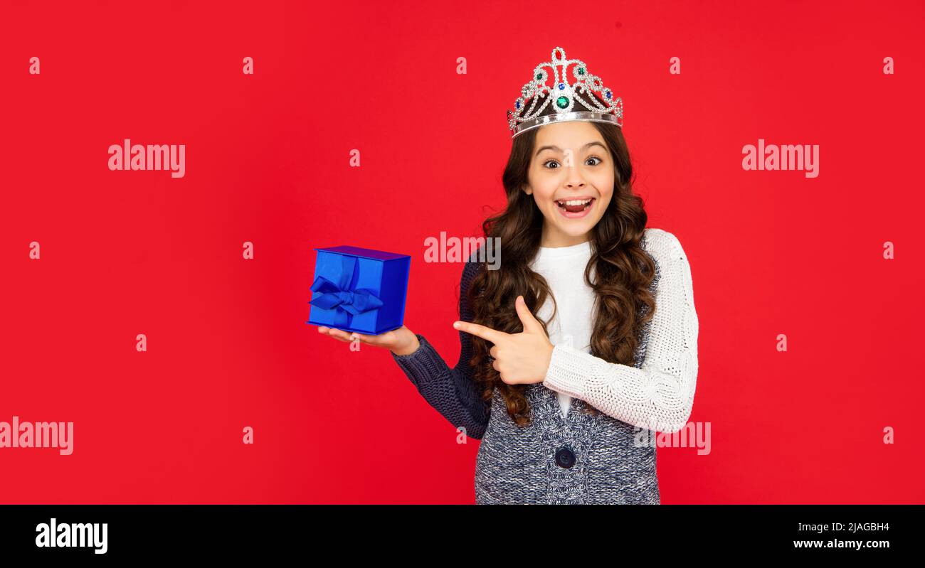 amazed child in queen crown. princess in tiara pointing finger on box ...