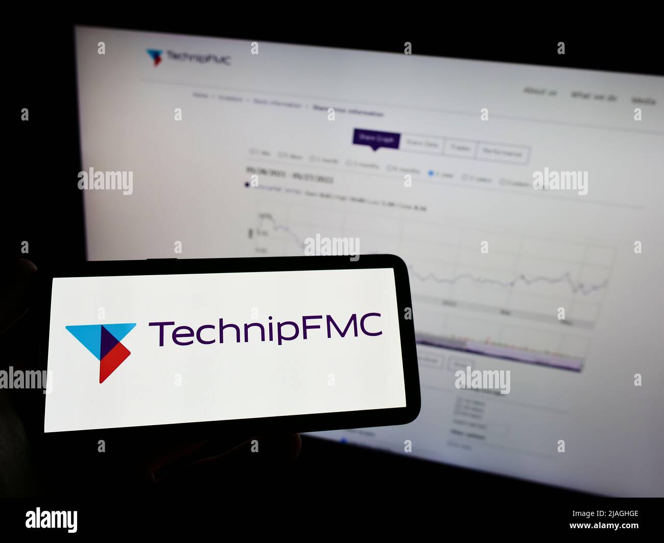 Person holding mobile phone with logo of oil and gas company TechnipFMC ...