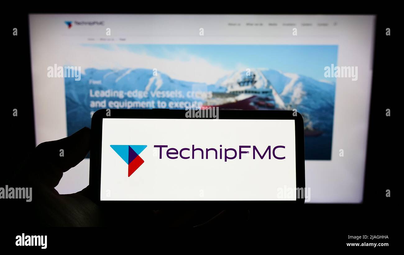 Person holding cellphone with logo of oil and gas company TechnipFMC ...