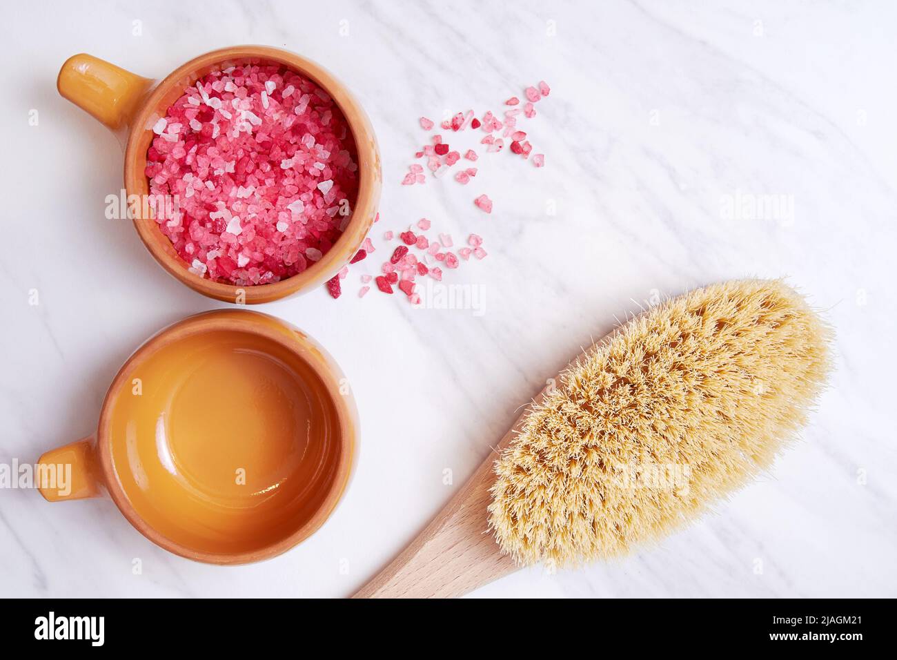 Bowl with the pink magnesium salt, wooden scrub brush on marble table ...