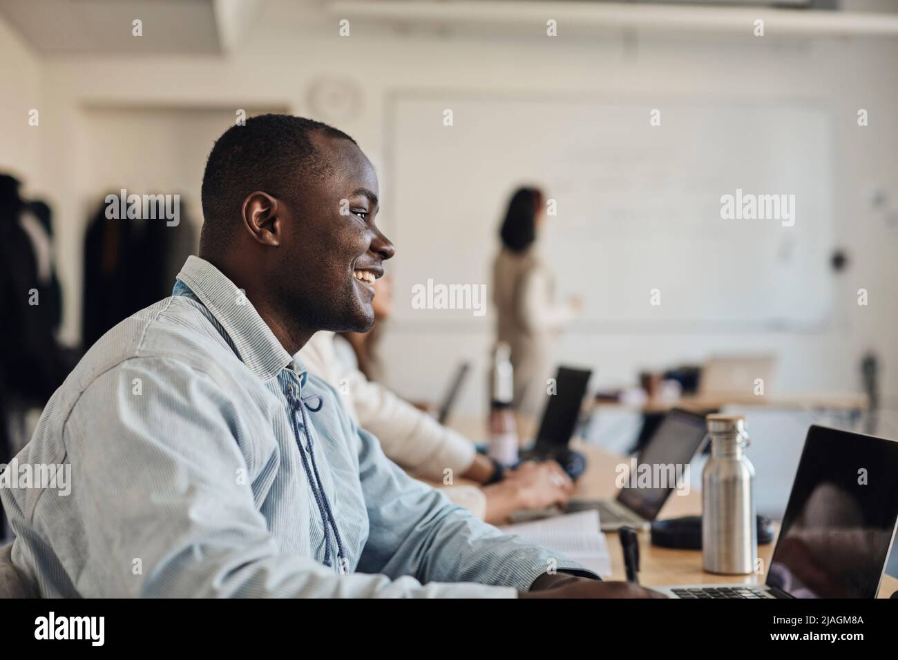 Side view of smiling male student with laptop in classroom Stock Photo ...