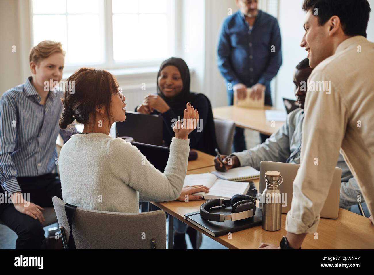 Female student explaining friends while sitting in classroom Stock ...