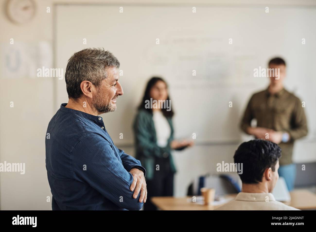 Side view of smiling male professor standing in classroom Stock Photo ...