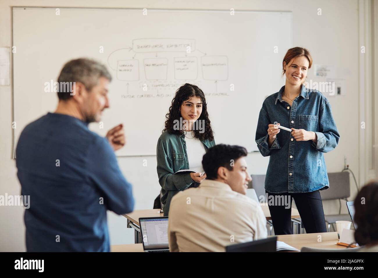 Young female students interacting with friends during lecture in ...