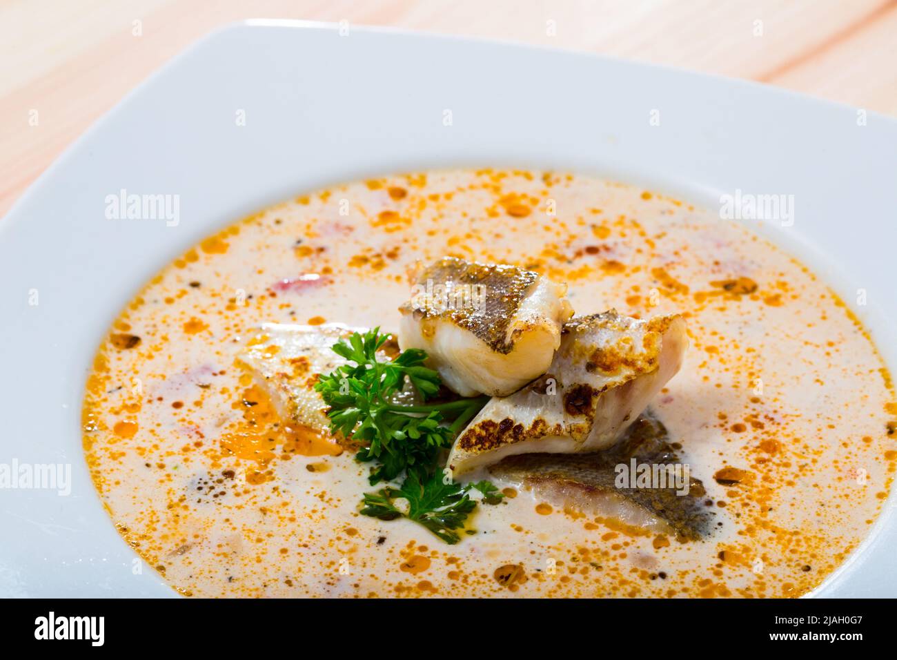 Tasty creamy soup with white fish cod and greens at white plate Stock ...