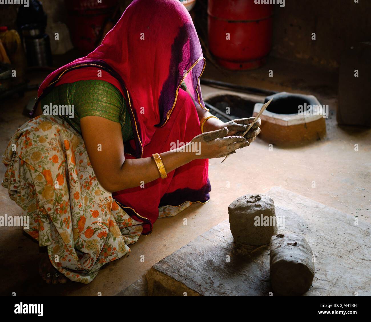 Unidentified woman in colourful traditional clothes and veil kneads ...