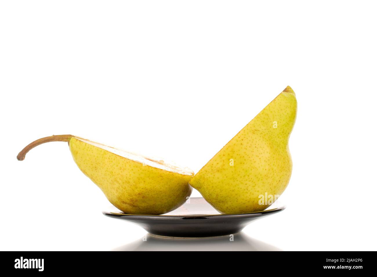 Two halves of a juicy yellow pear on a ceramic saucer, close-up ...