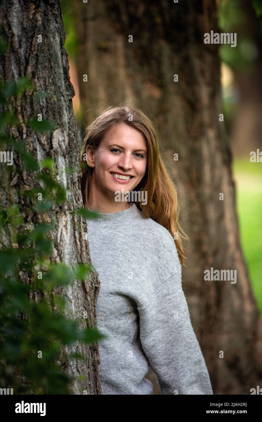 portrait of blond woman standing between trees Stock Photo - Alamy