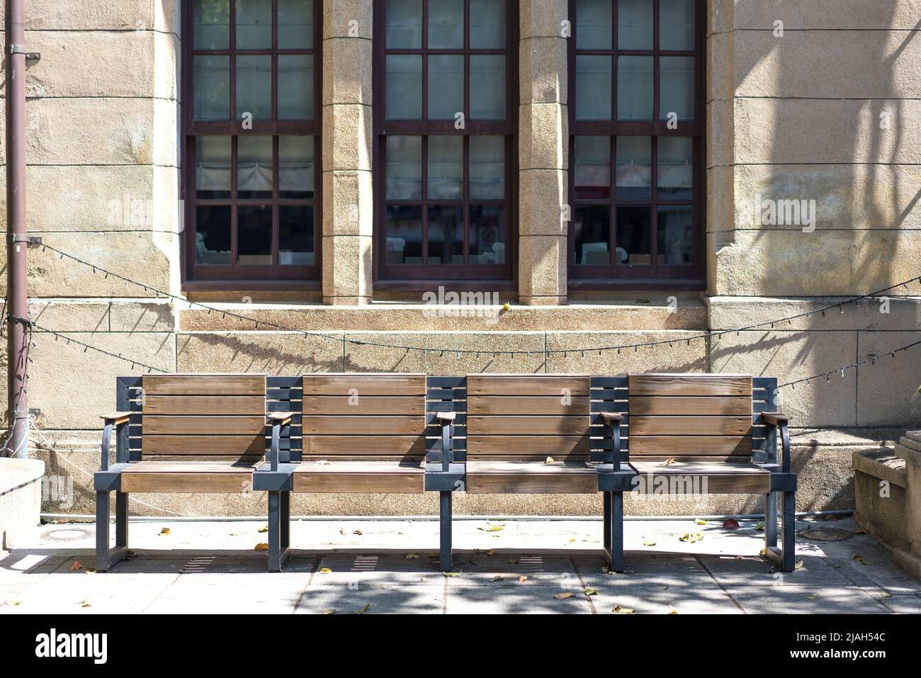 wooden bench next to stone walkway in front of old building with ...