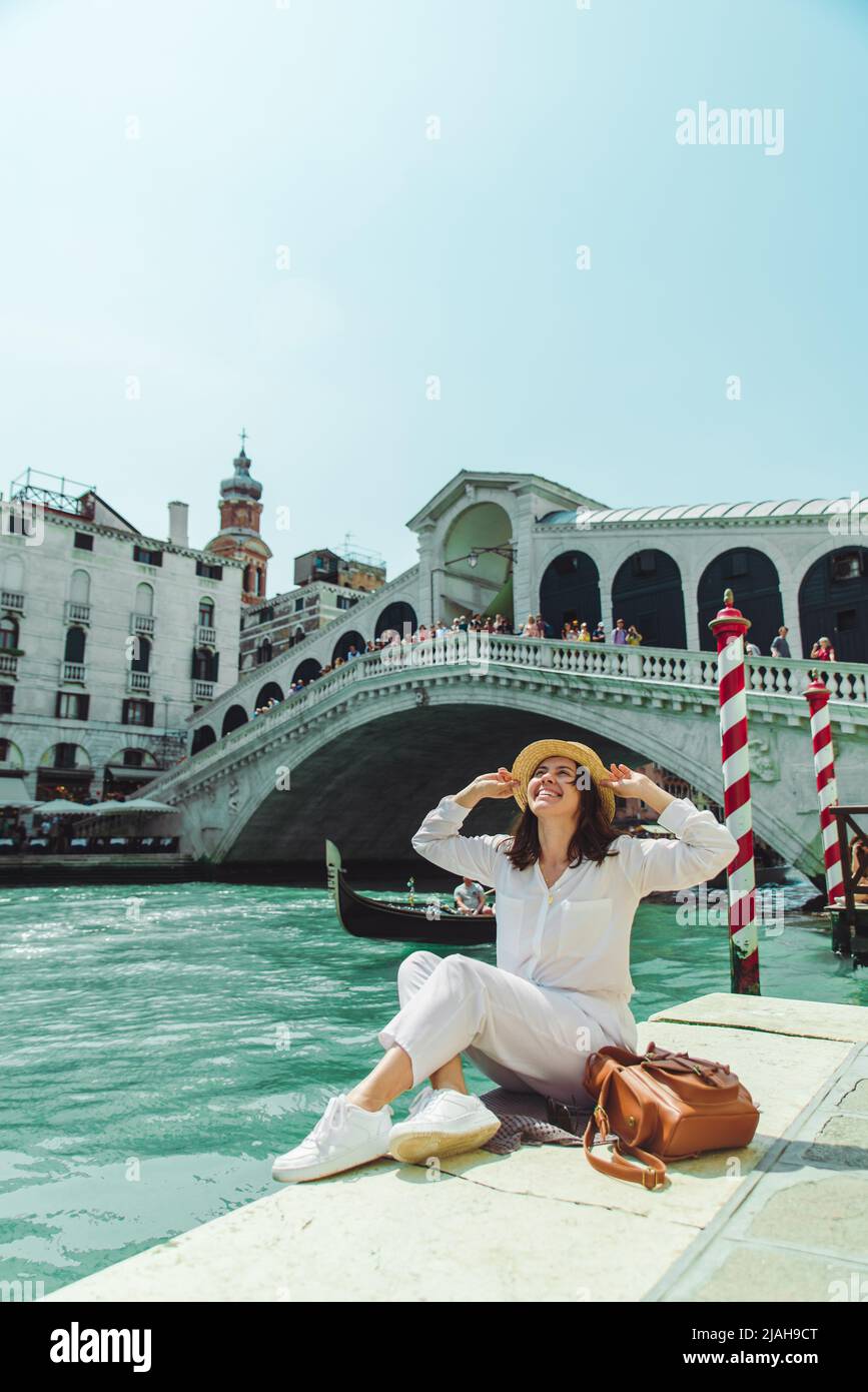 woman sitting near rialto bridge in venice italy looking at grand canal ...