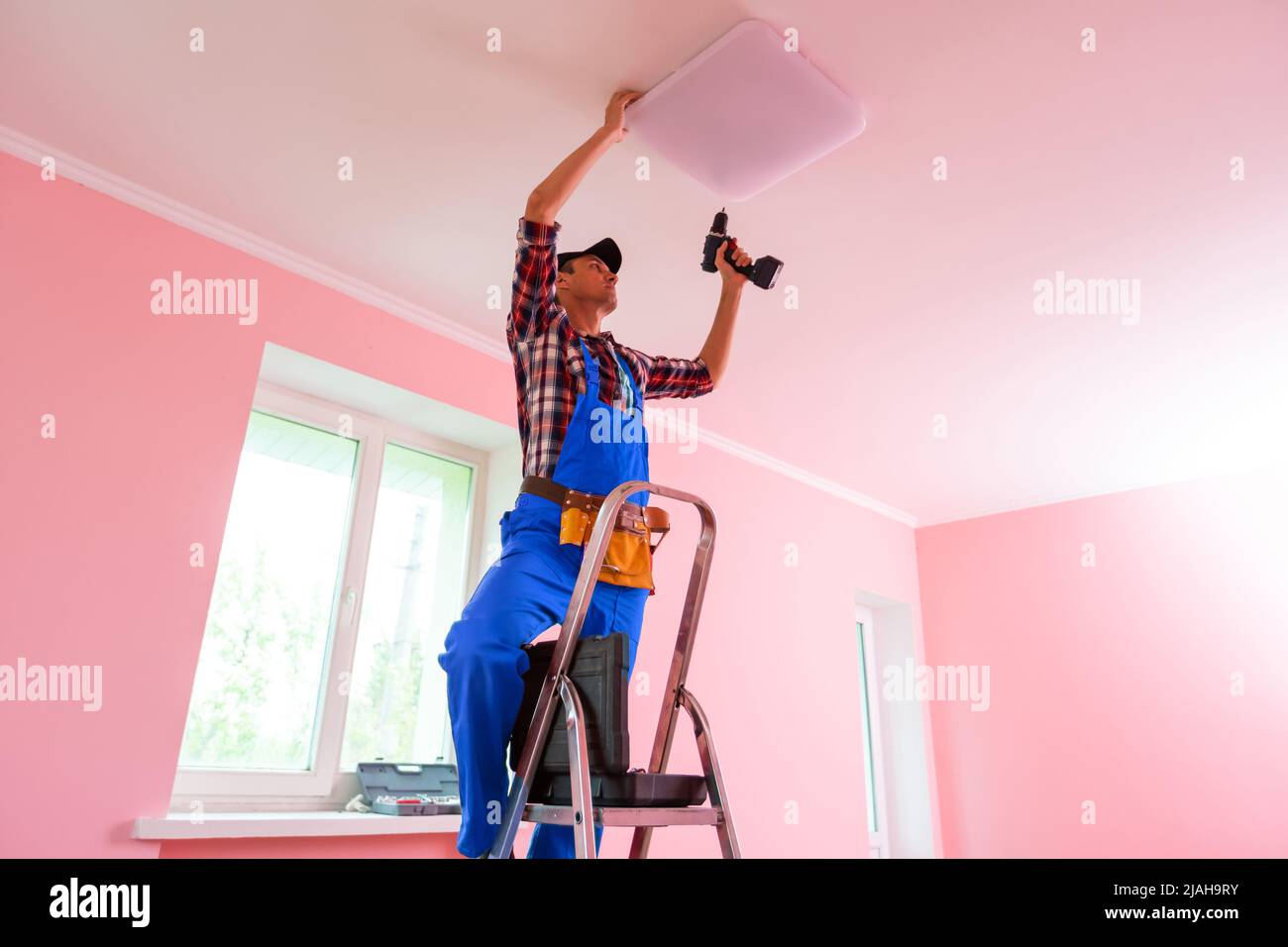 Electrician changing light bulb. Young man in overall work uniform ...