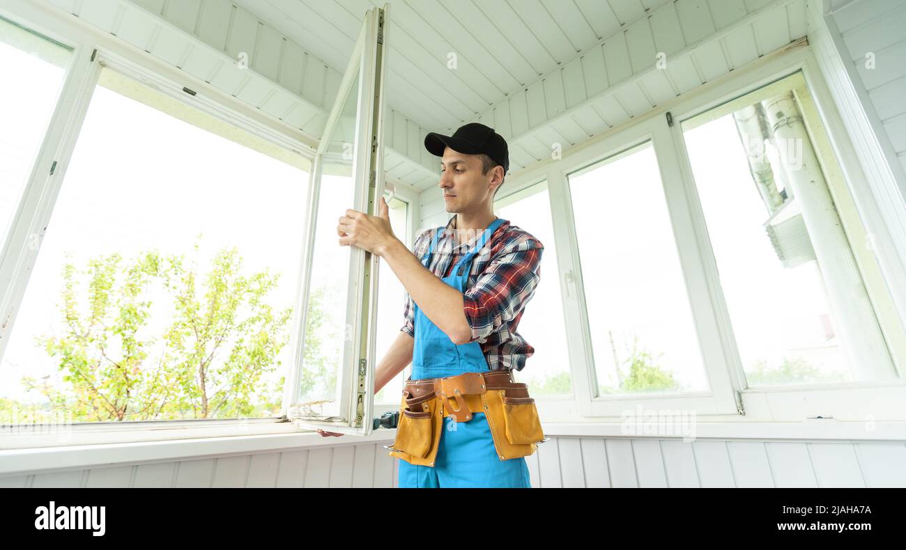 handyman adjusting white pvc plastic window indoors. worker using ...