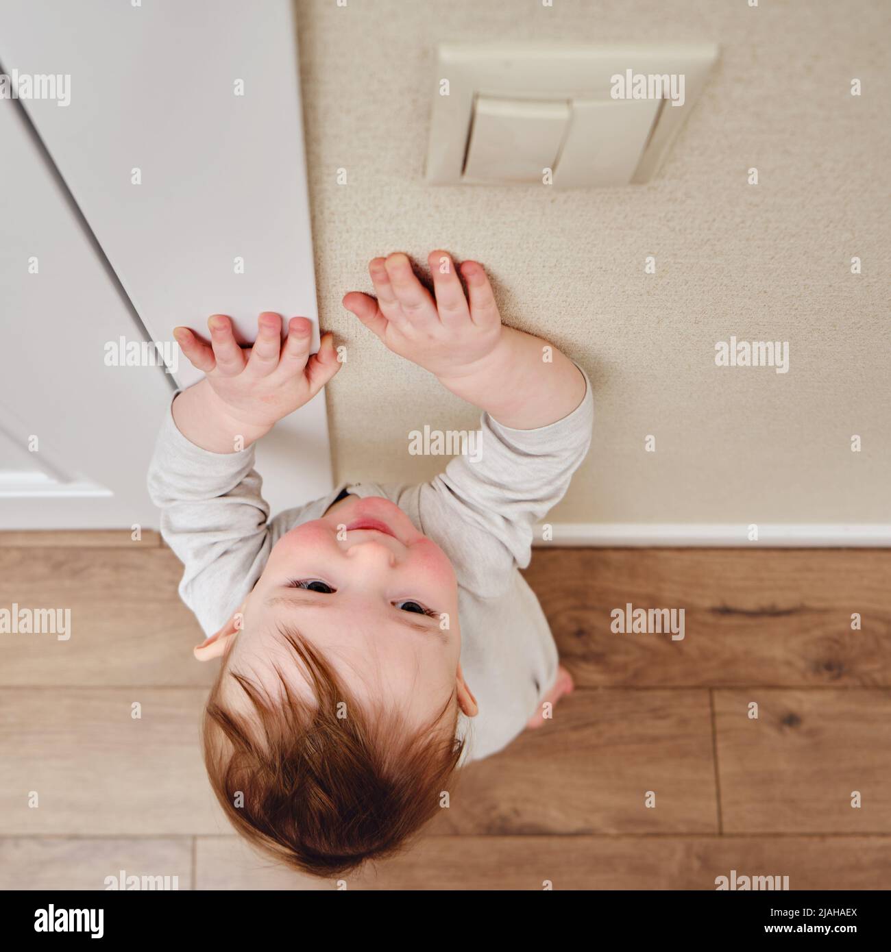 Toddler baby boy reaches for the light switch. Child turns on the light ...
