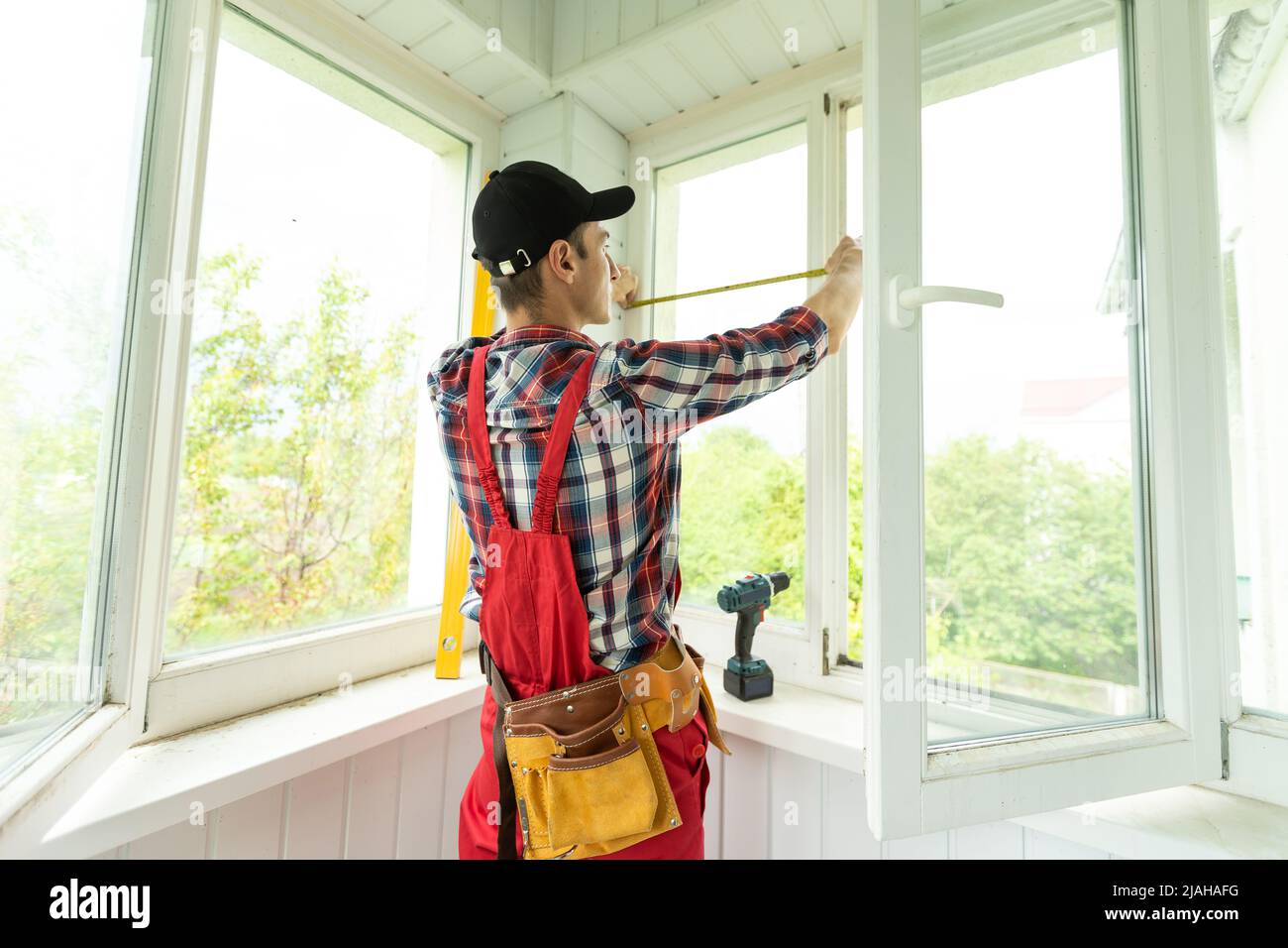 Man measuring window prior to installation of roller shutter outdoors ...