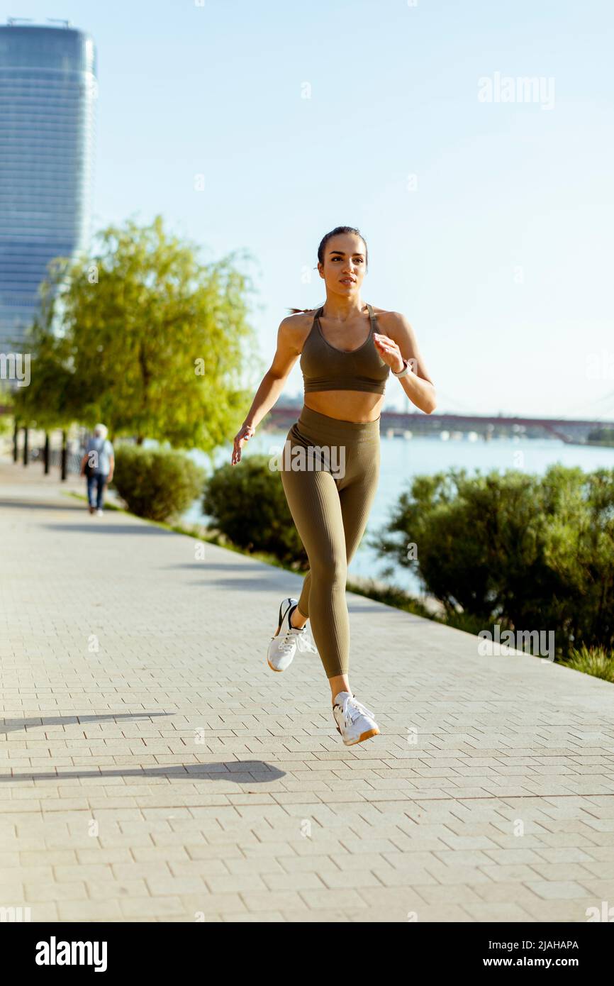 Pretty young woman taking running exercise by the river promenade Stock ...