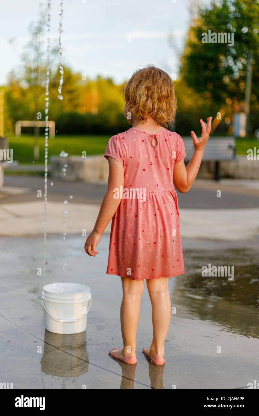 Little girl playing with water at splash pad in summer. Child at ...