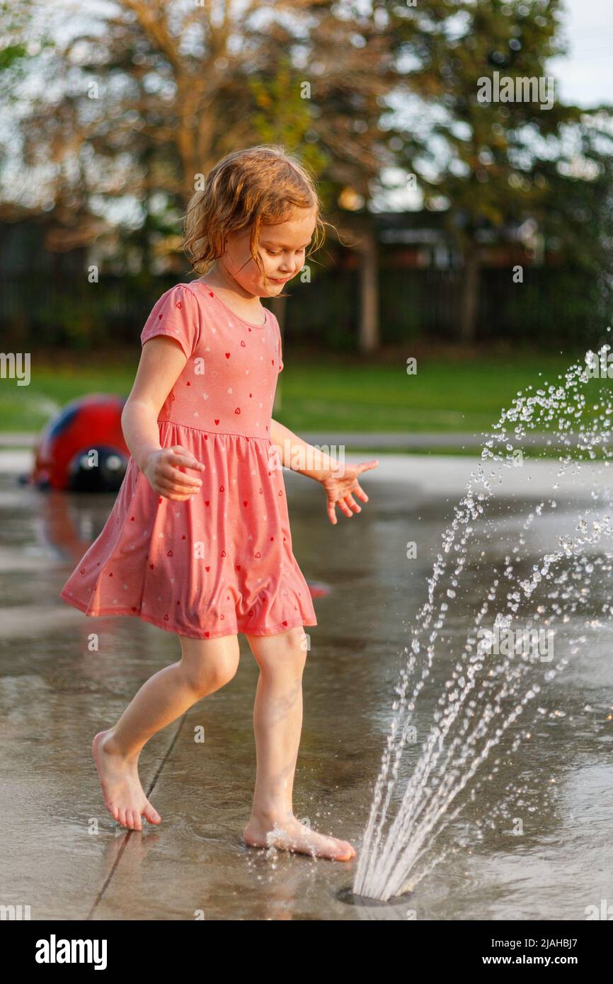 Happy smiling child playing at splash pad with water. Little girl ...