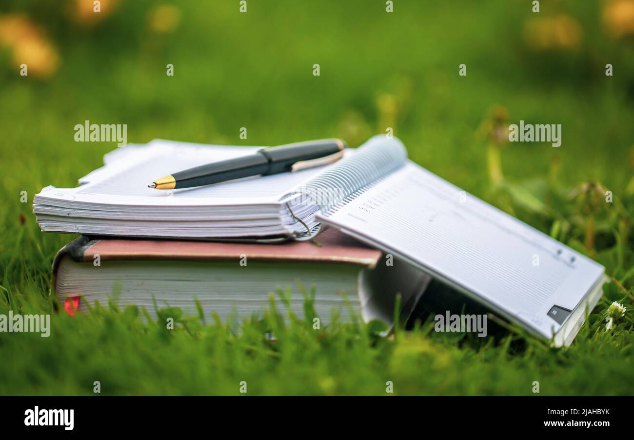 Organizer and book outdoor in grass of a park Stock Photo - Alamy