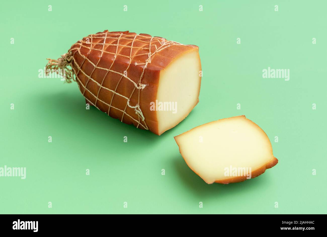 Close-up with a big chunk of smoked cheese on a green table. Smoked ...