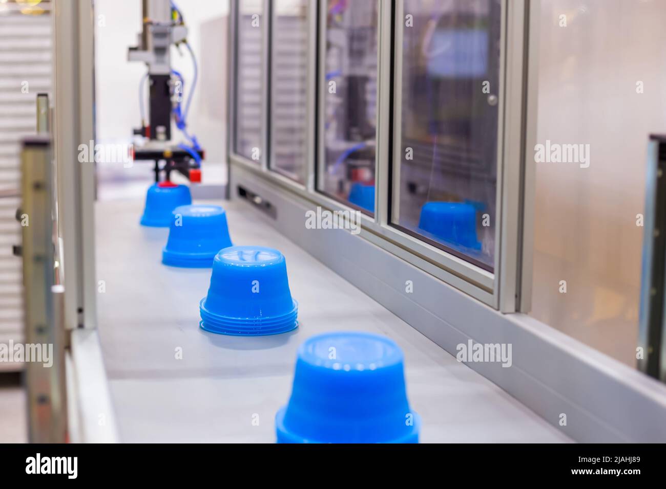 Blue pots on conveyor belt of plastic injection molding machine with ...