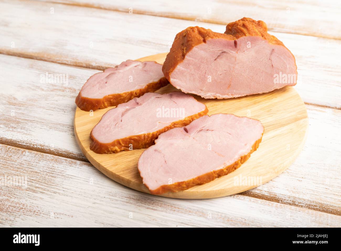 Smoked pork ham on cutting board on white wooden background. Side view ...