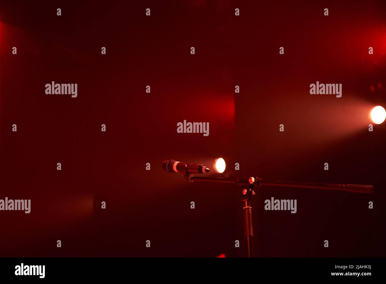Professional stage microphone in a bright red spotlight on a dark ...