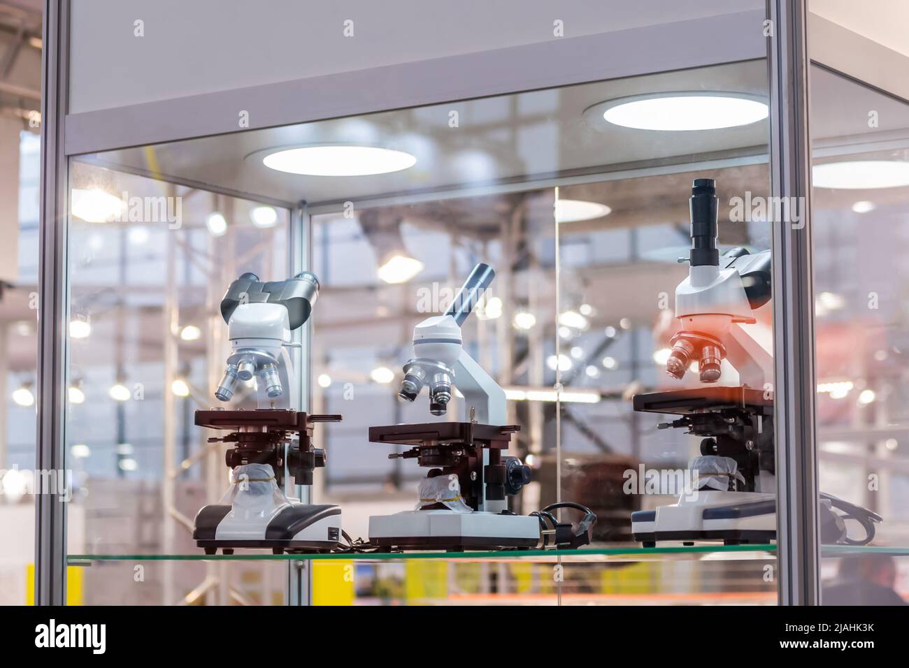 Three microscopes in glass showcase at science exhibition - laboratory ...