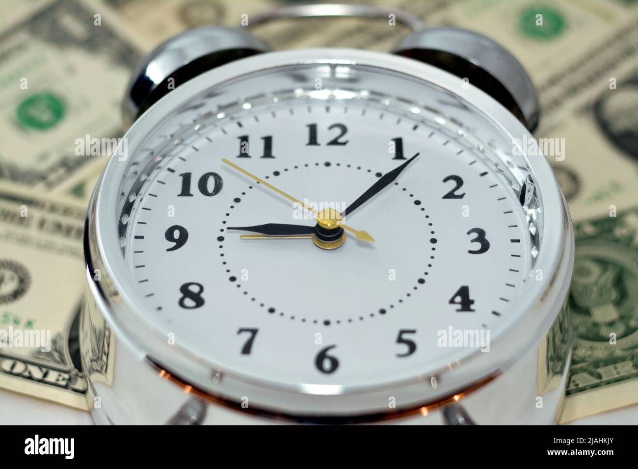 An alarm clock on a background of blurred American money banknote ...