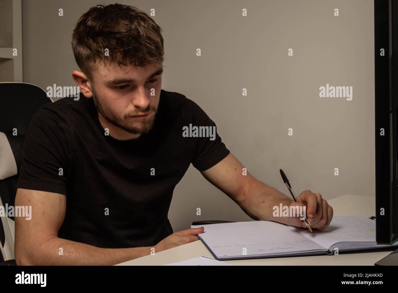 A University Aged Male Student doing coursework at a desk Stock Photo ...