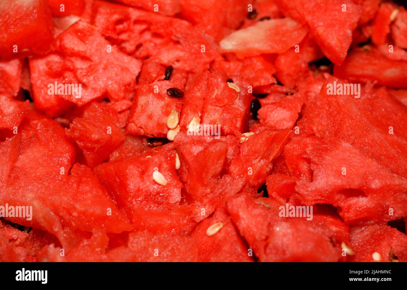 A closeup of a pile of watermelon fruit cuts into small pieces with ...