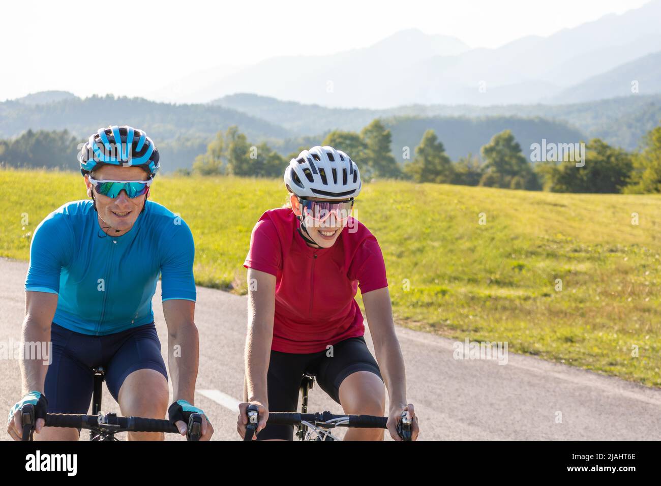 Smiling happy road cyclist couple riding uphill side by side Stock ...