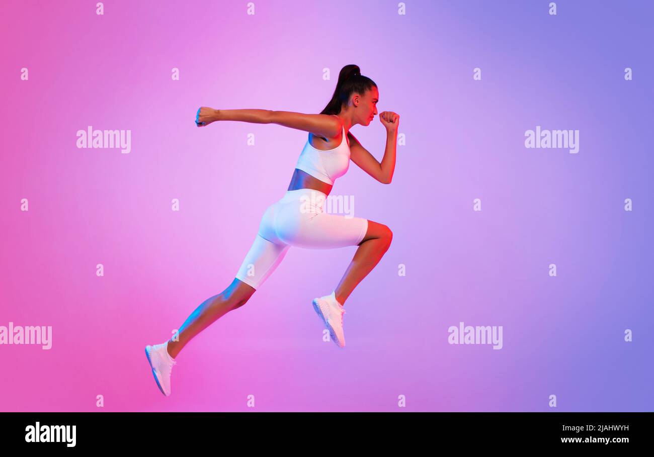 Sporty Lady Running In Mid Air Over Pink Neon Background Stock Photo ...