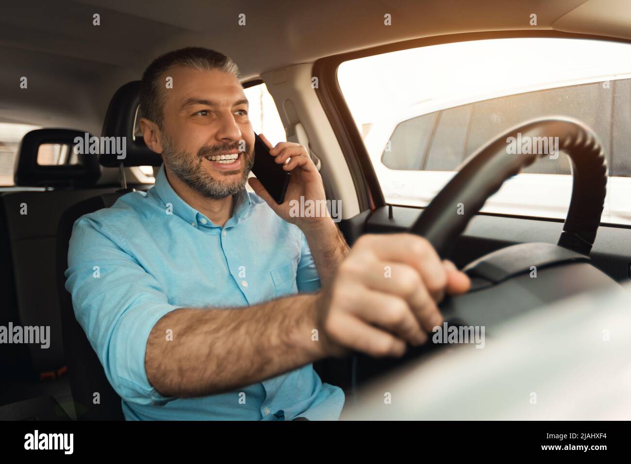 Happy man talking on smartphone while driving car Stock Photo - Alamy