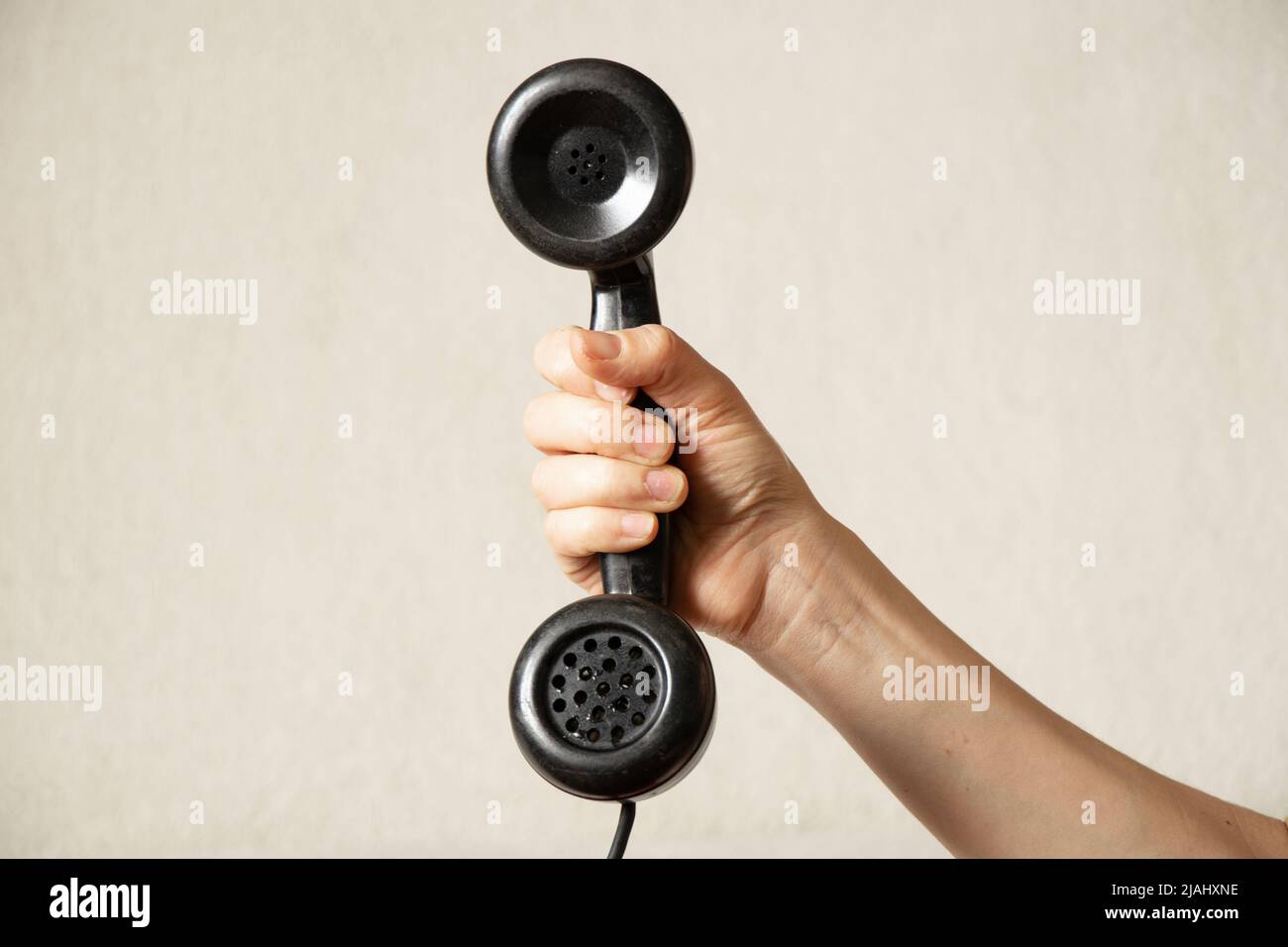 A woman's hand holds a telephone old black tube on a white background ...