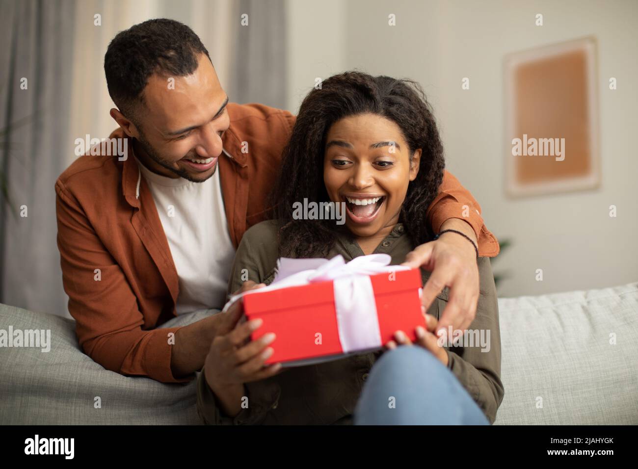 Happy Black Husband Giving Gift Box To Wife At Home Stock Photo - Alamy