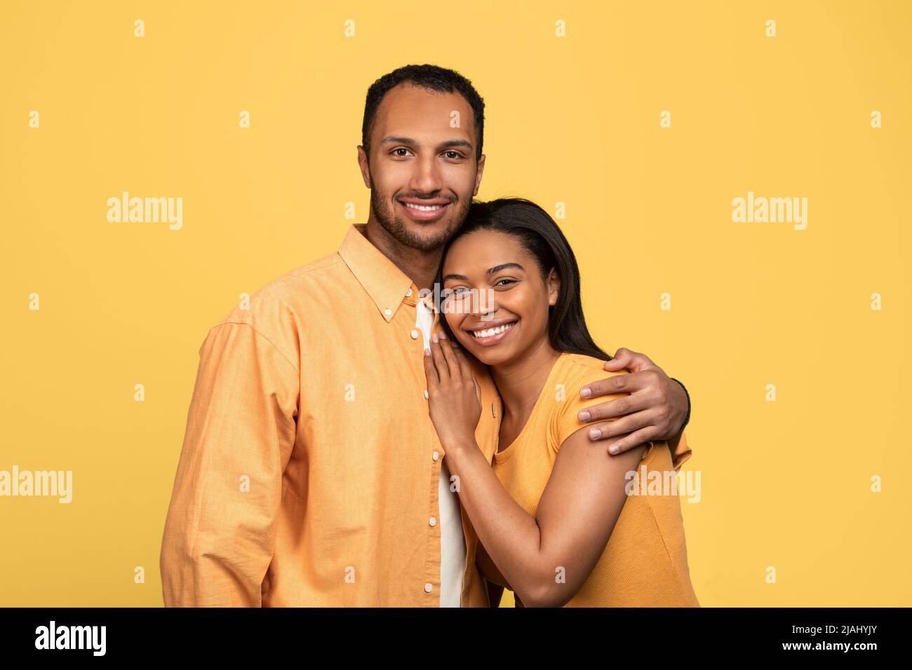 Portrait of affectionate young black couple embracing and looking at ...