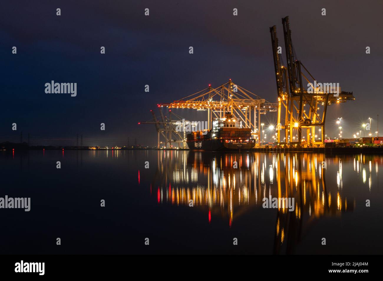 Cargo ship loading at Southampton container terminal at night viewed ...