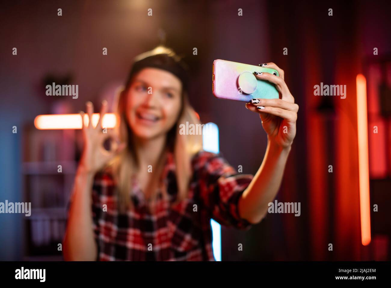 Adorable young woman wearing cap using modern smartphone for taking ...