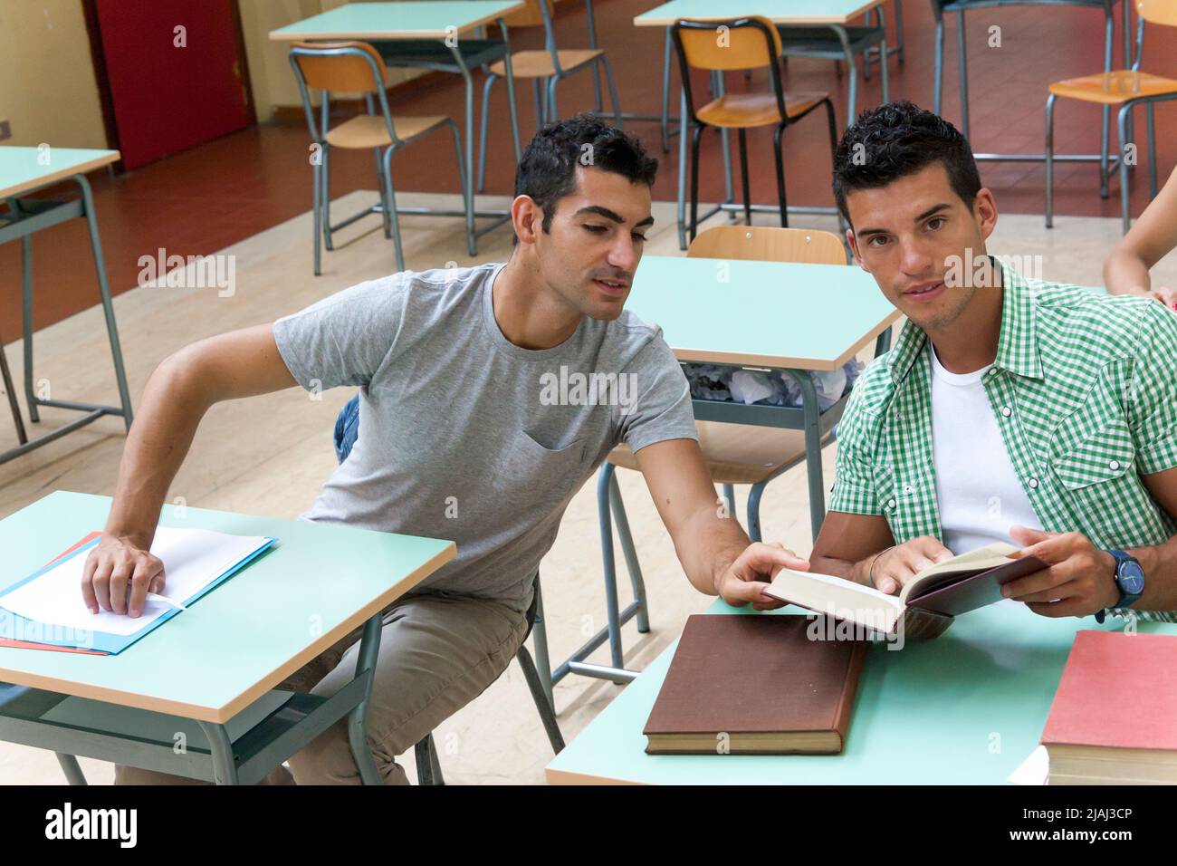 two young students rehearsing the lesson on books in the classroom ...