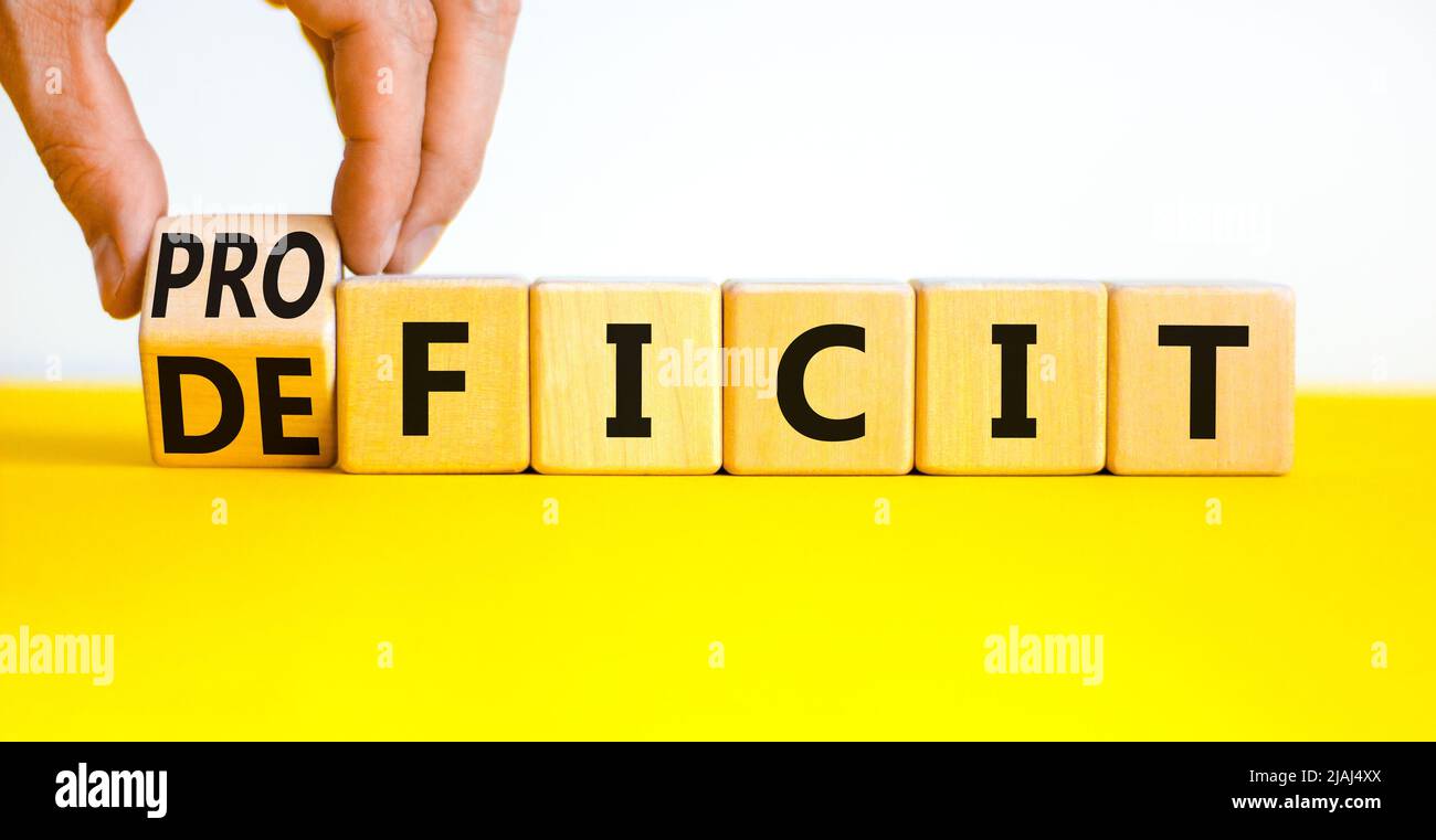 Proficit or deficit symbol. Businessman turns wooden cubes and changes the concept word deficit ...