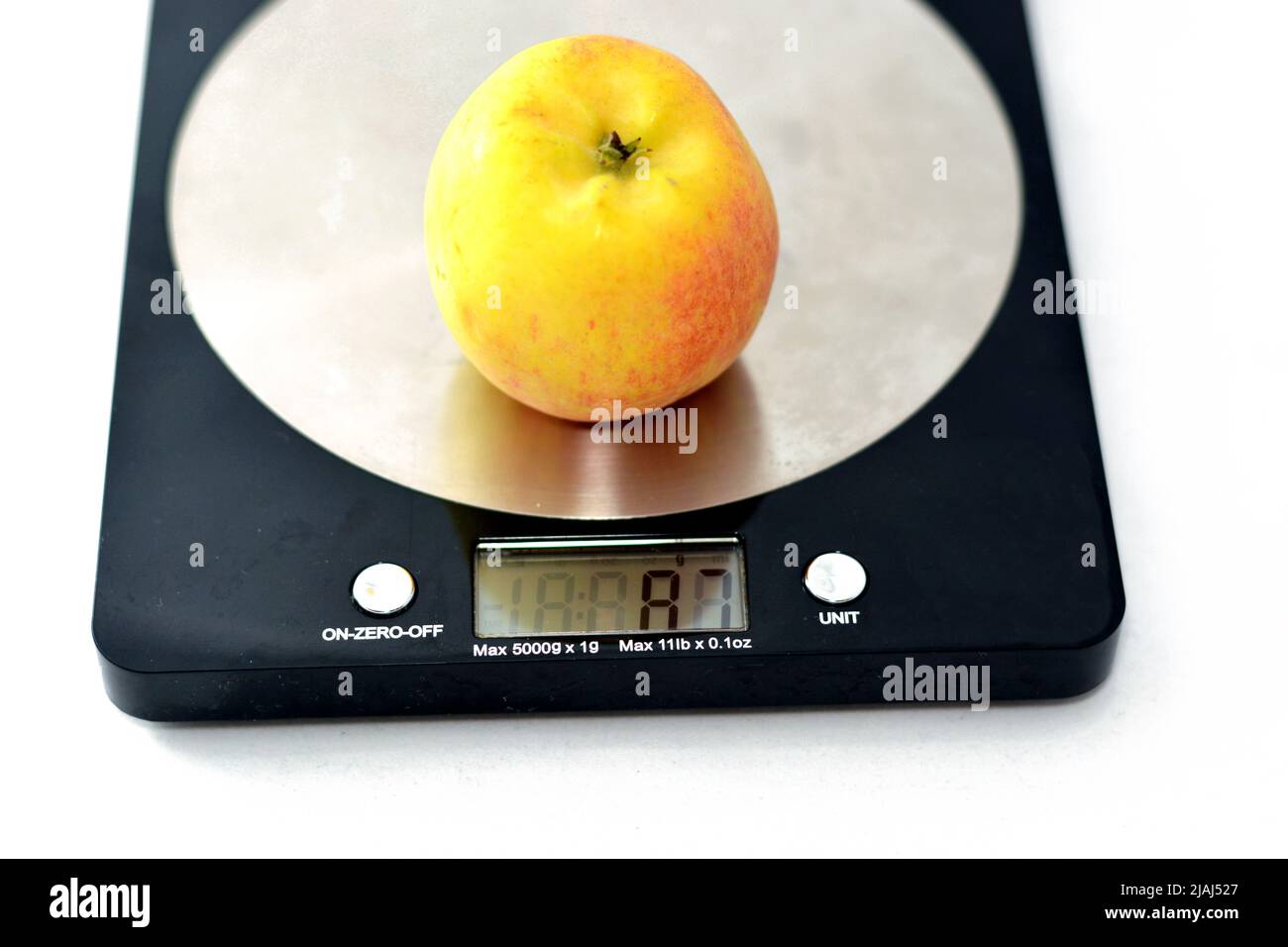 Weighing an Apple fruit on a digital kitchen scale in grams isolated on ...