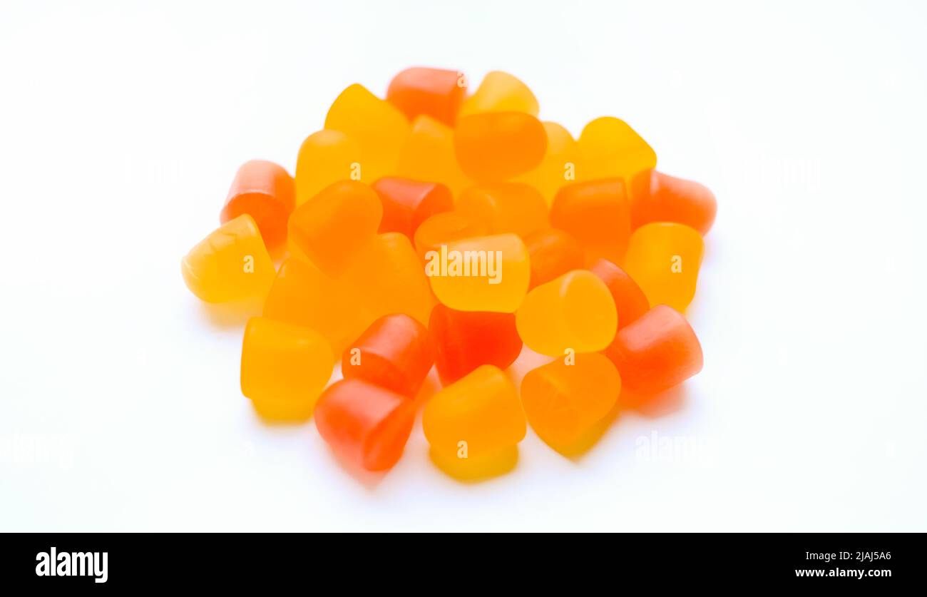 Close-up texture of orange and yellow multivitamin gummies in the form ...