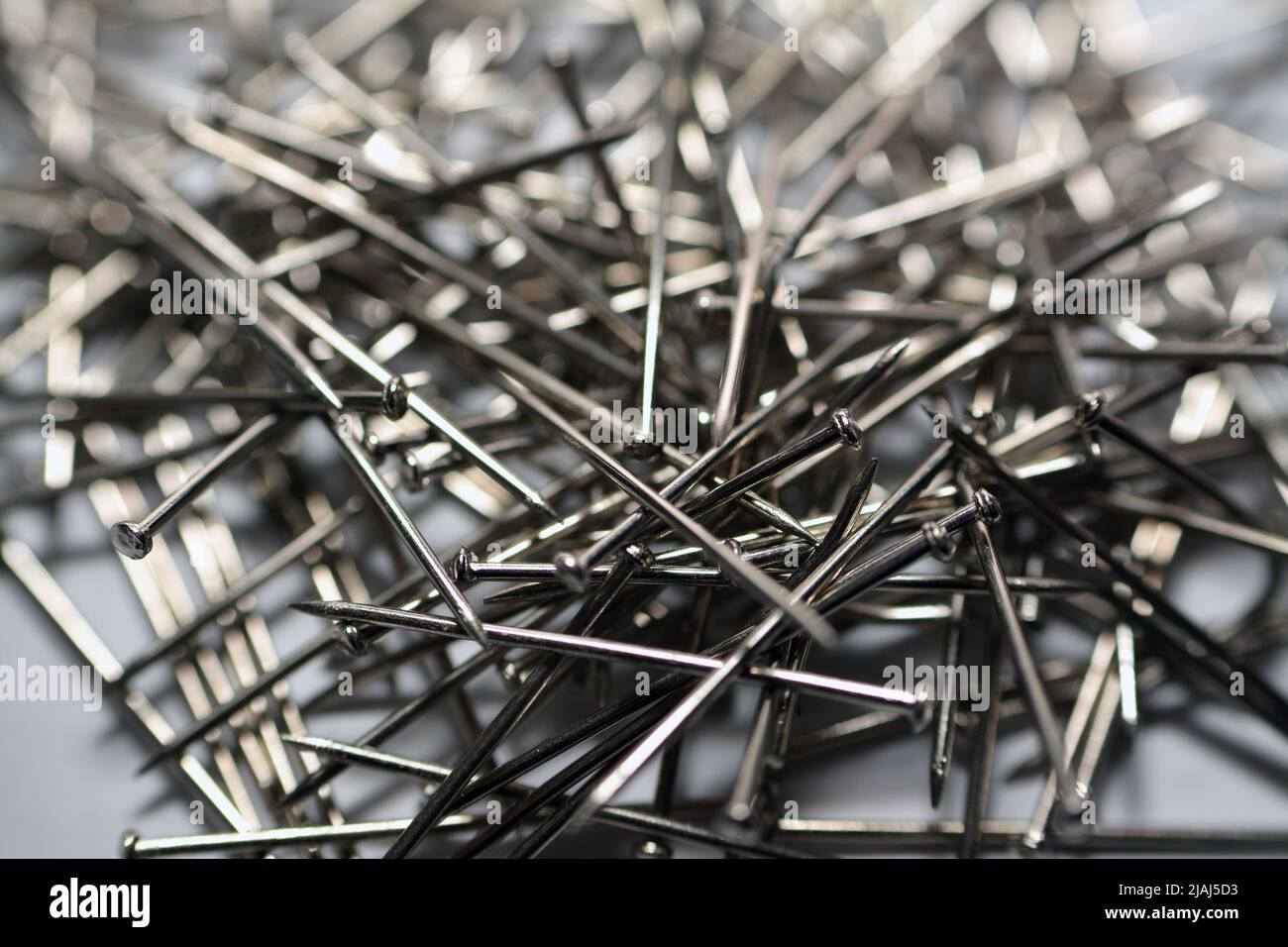 Selective focus of a pile of Nickel plated steel pins, stack of paper ...