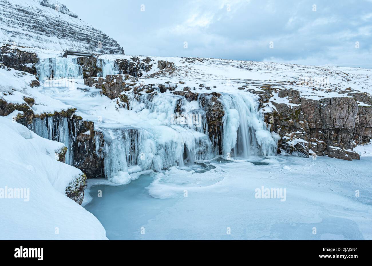 The frozen waterfall of Kirkjufellfoss in Iceland in Winter covered in ...