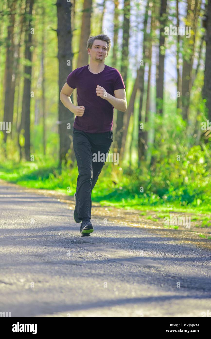 Running man jogging in city park at beautiful summer day. Sport fitness ...