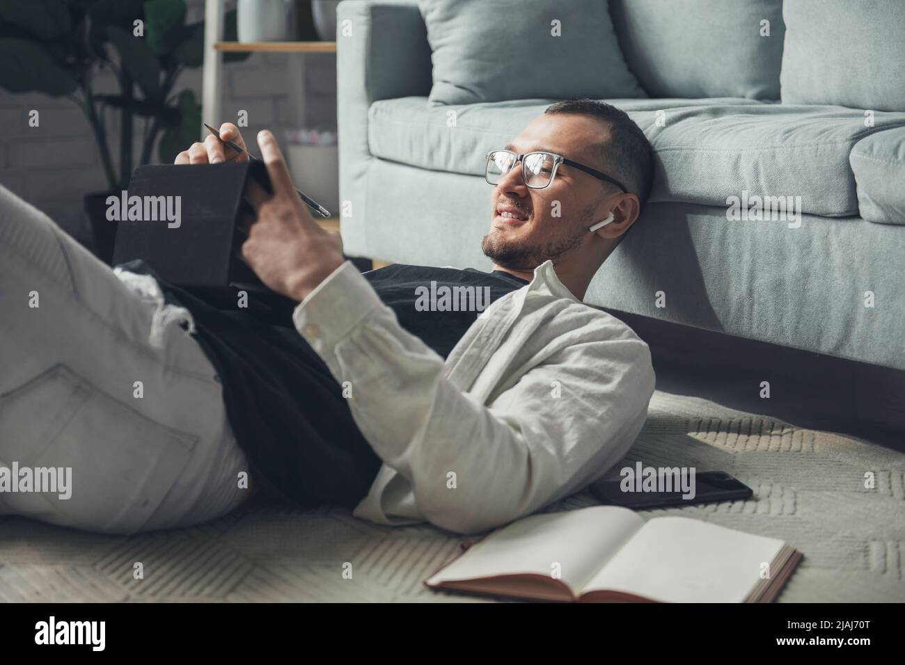 Man with wireless headphones using gadgets, talking and smiling while ...