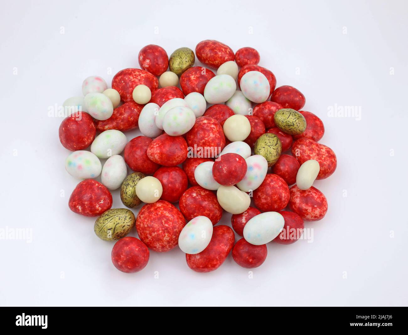 Colored dragees on a white background. Candies round in red glaze close ...